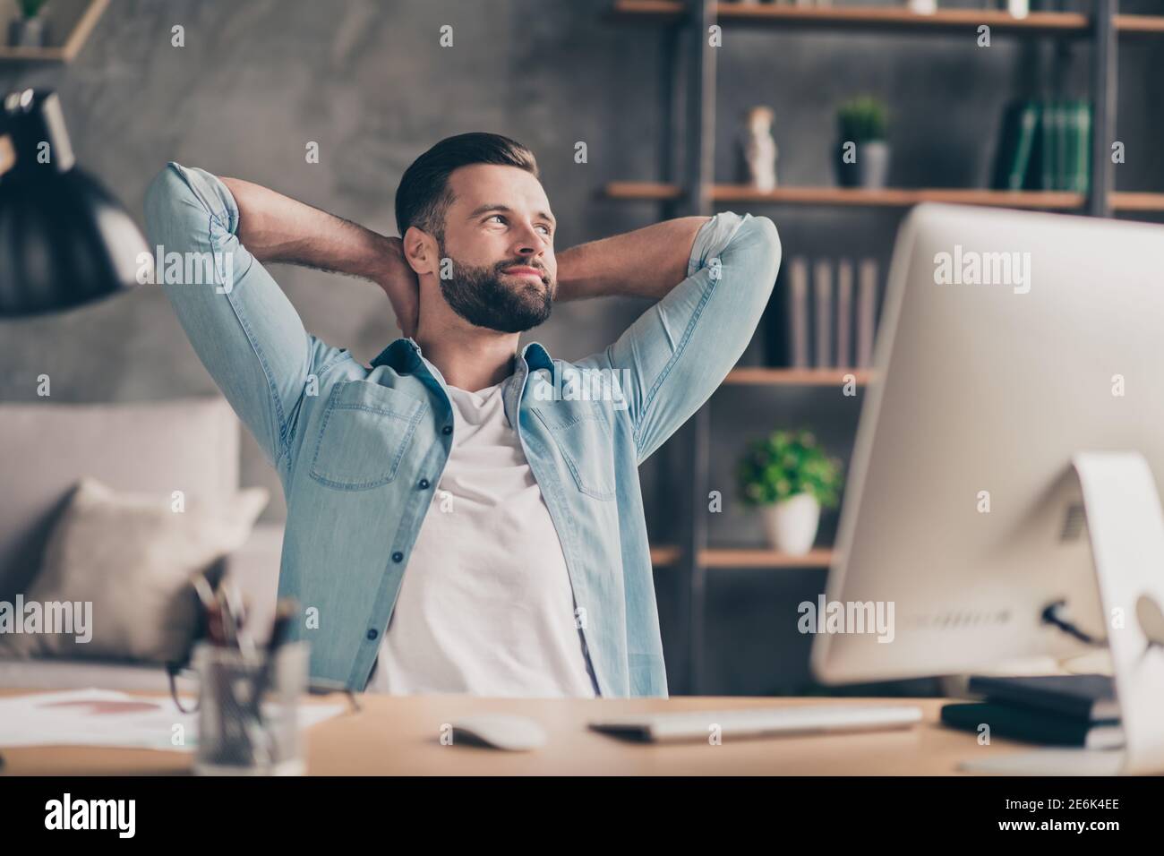 Photo portrait of dreamy guy resting with hands behind back at table in ...