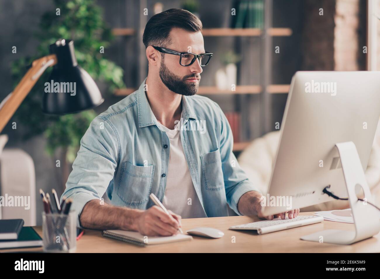 Photo portrait of smart guy taking notes working on computer at desk in ...
