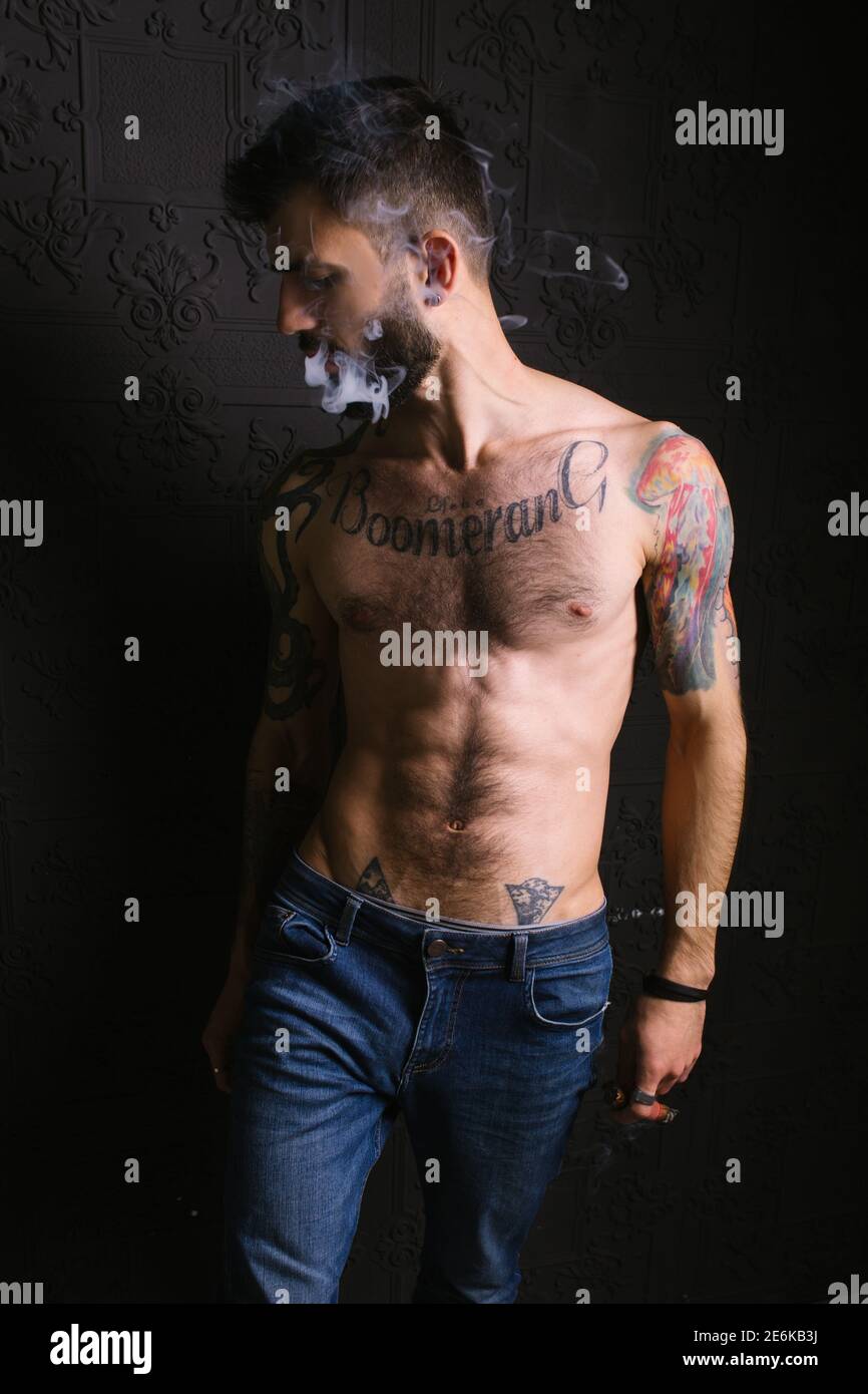 Portrait of a brutal beard gentleman with tattoo body smoking cigar in ...