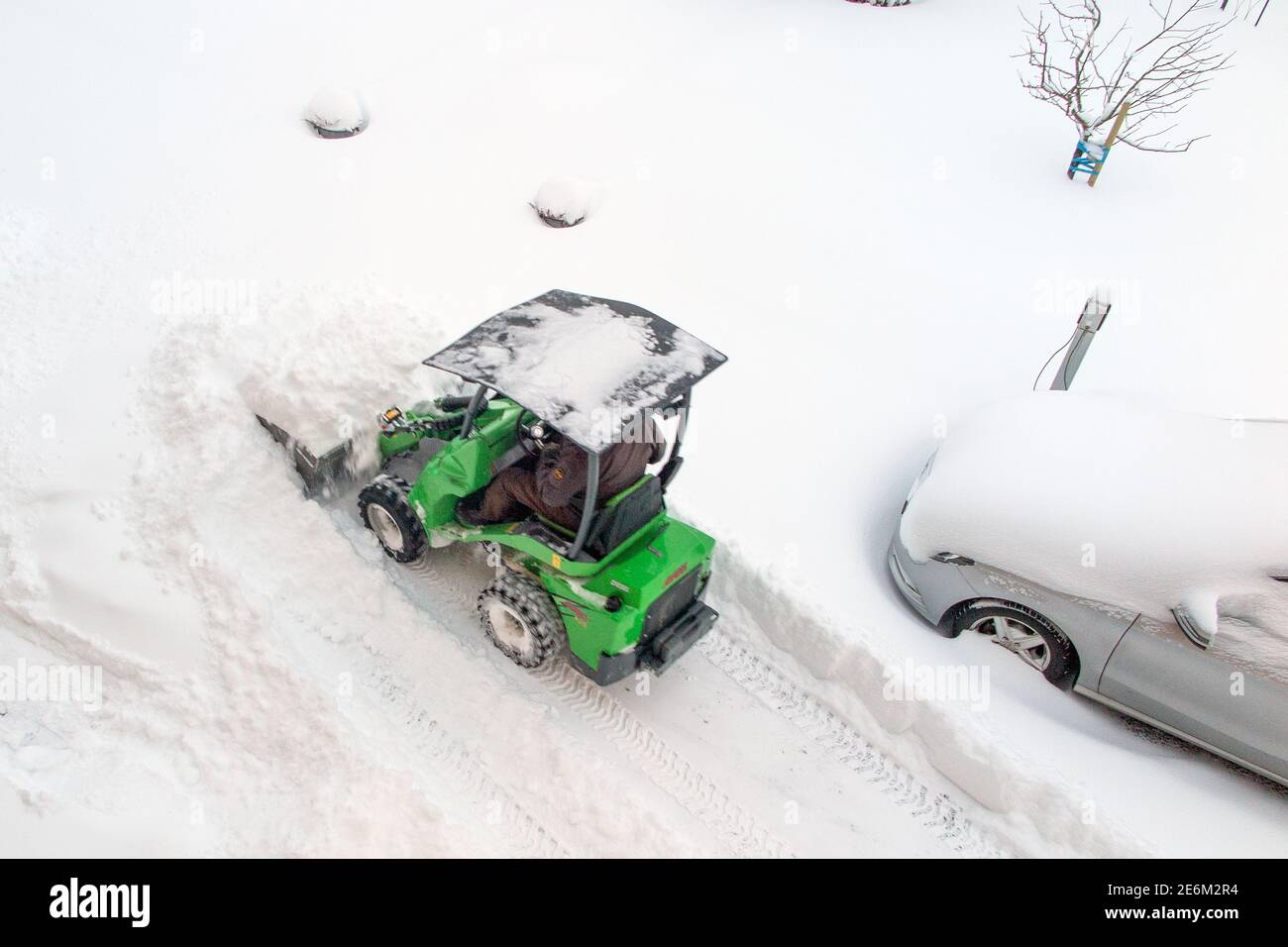 A small urban snow removal machine works in the courtyard. View from ...