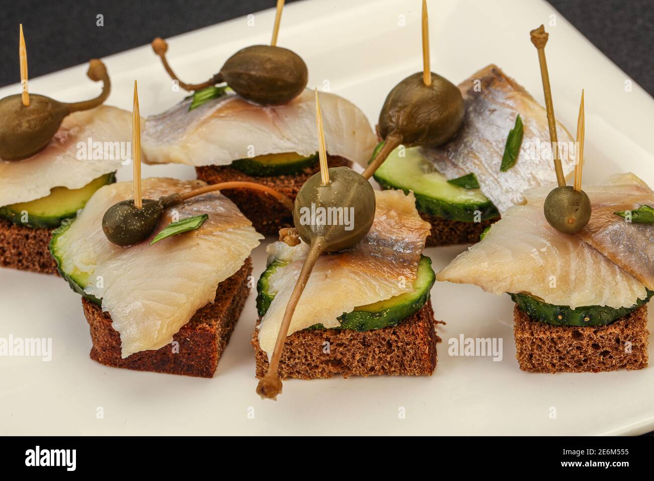 Herring fillet canape snack with caperberry and cucumber Stock Photo ...