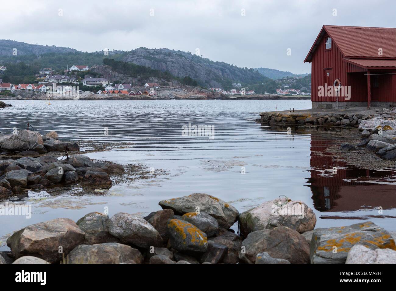 Red boathouse on a small peninsula by sunset at the coast of Lindesnes ...
