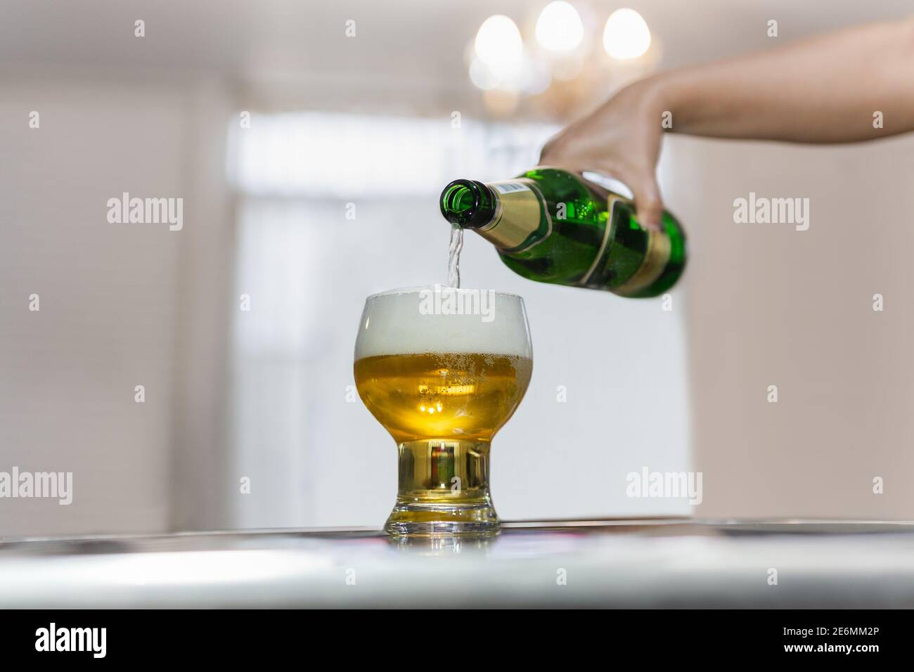 Hand pouring beer from green bottle into glass Stock Photo - Alamy