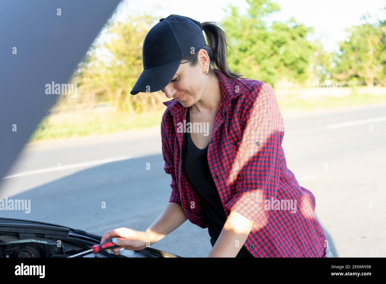 Beautiful young woman fixing the car on the roadside . Girl in shirt ...