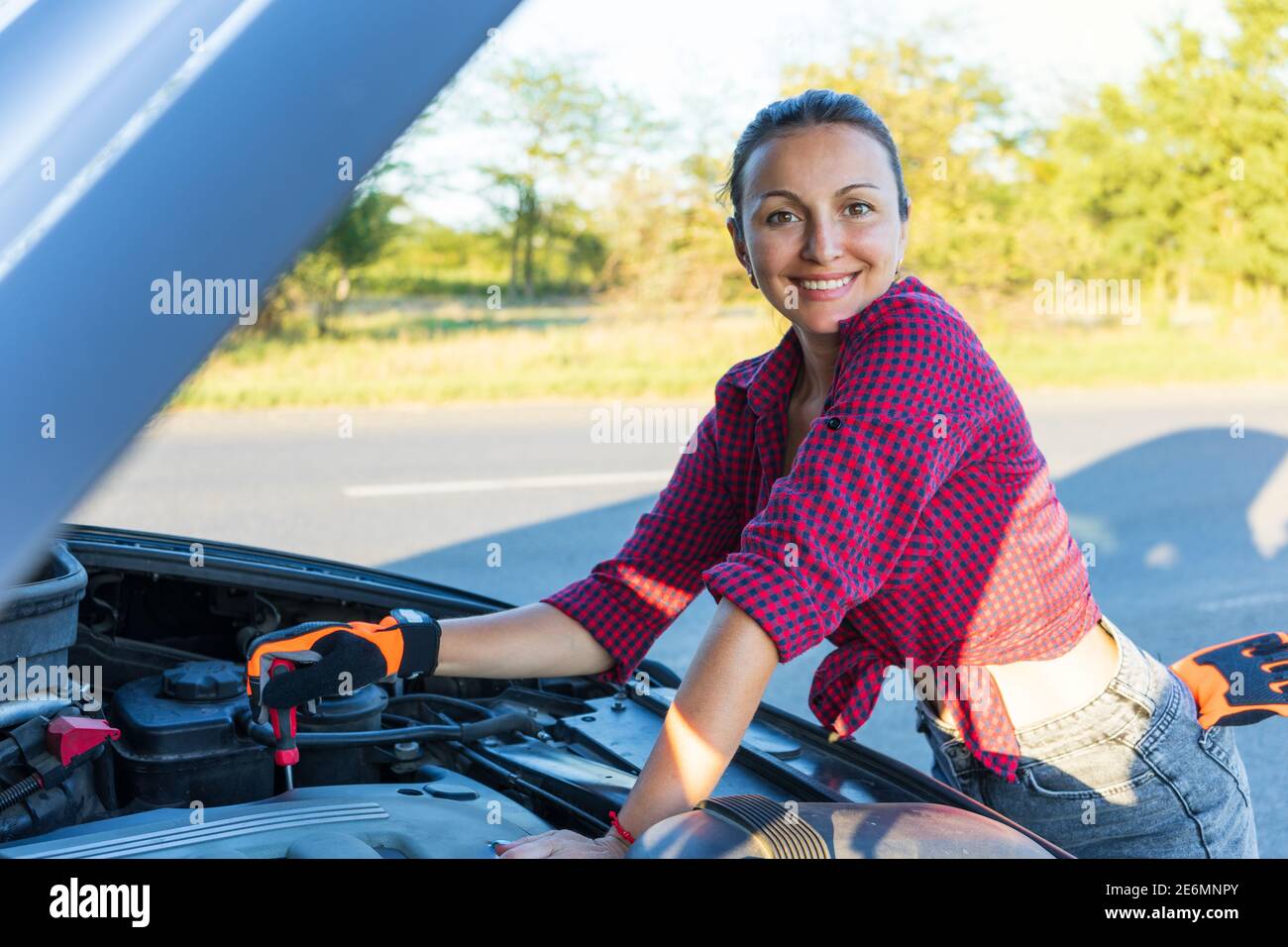 Beautiful young woman fixing the car on the roadside . Girl in shirt ...