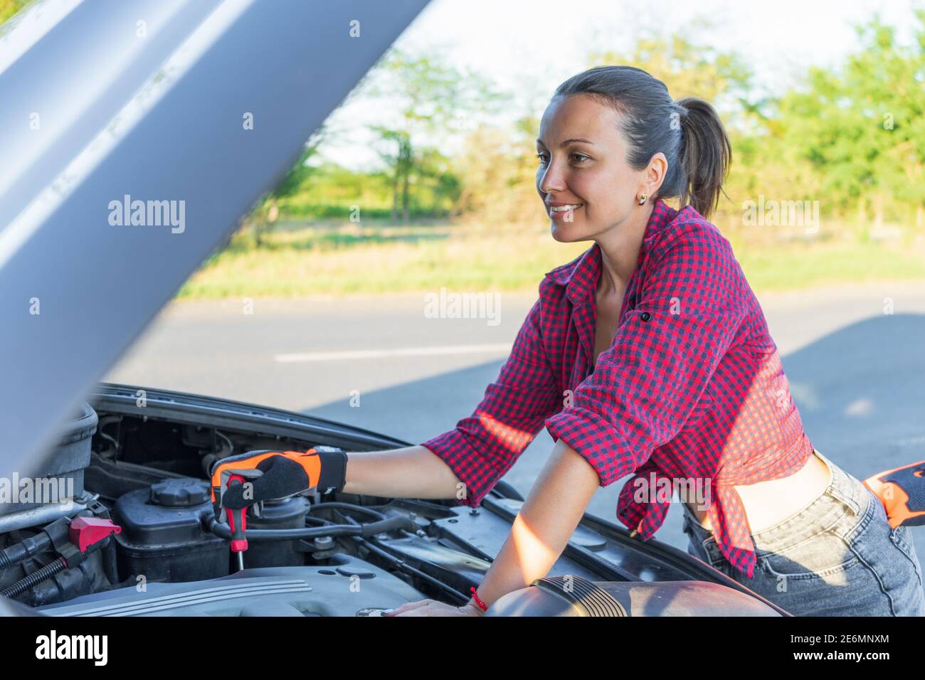Beautiful young woman fixing the car on the roadside . Girl in shirt ...
