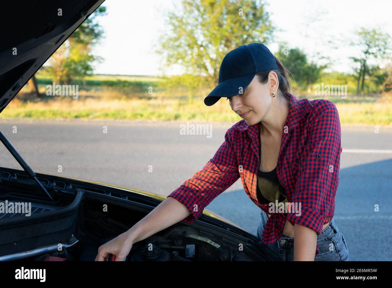 Beautiful young woman fixing the car on the roadside . Girl in shirt ...