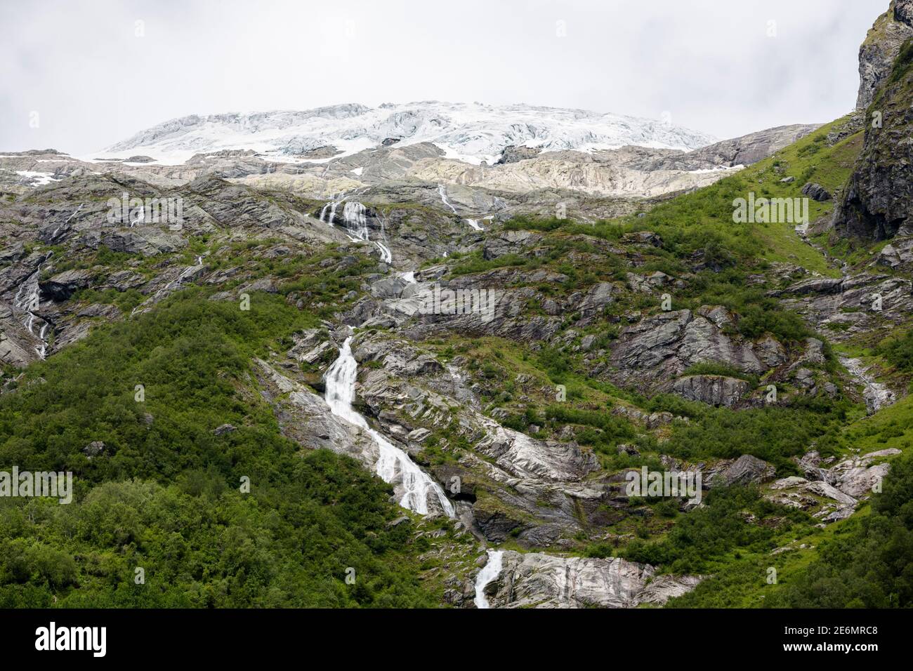 Boyabreen Glacier and waterfalls running down the cragged and forested ...