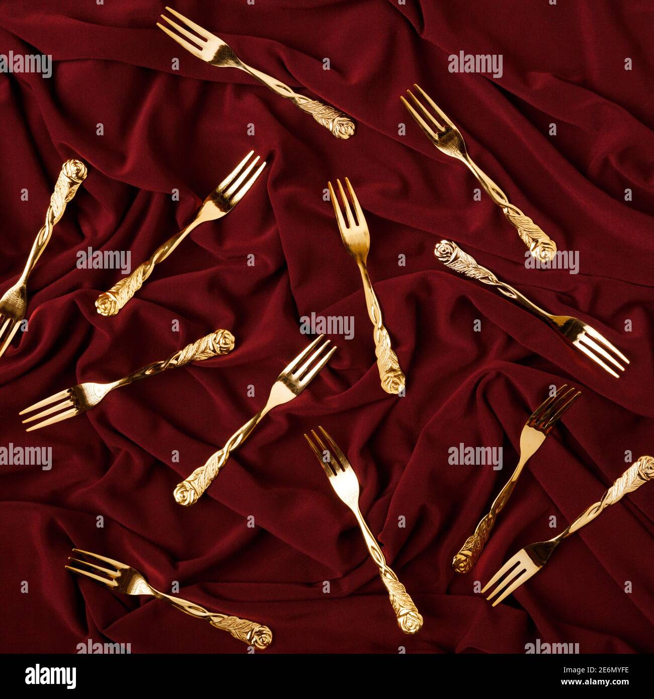 Bunch of golden shiny forks against cloth background in the maroon ...