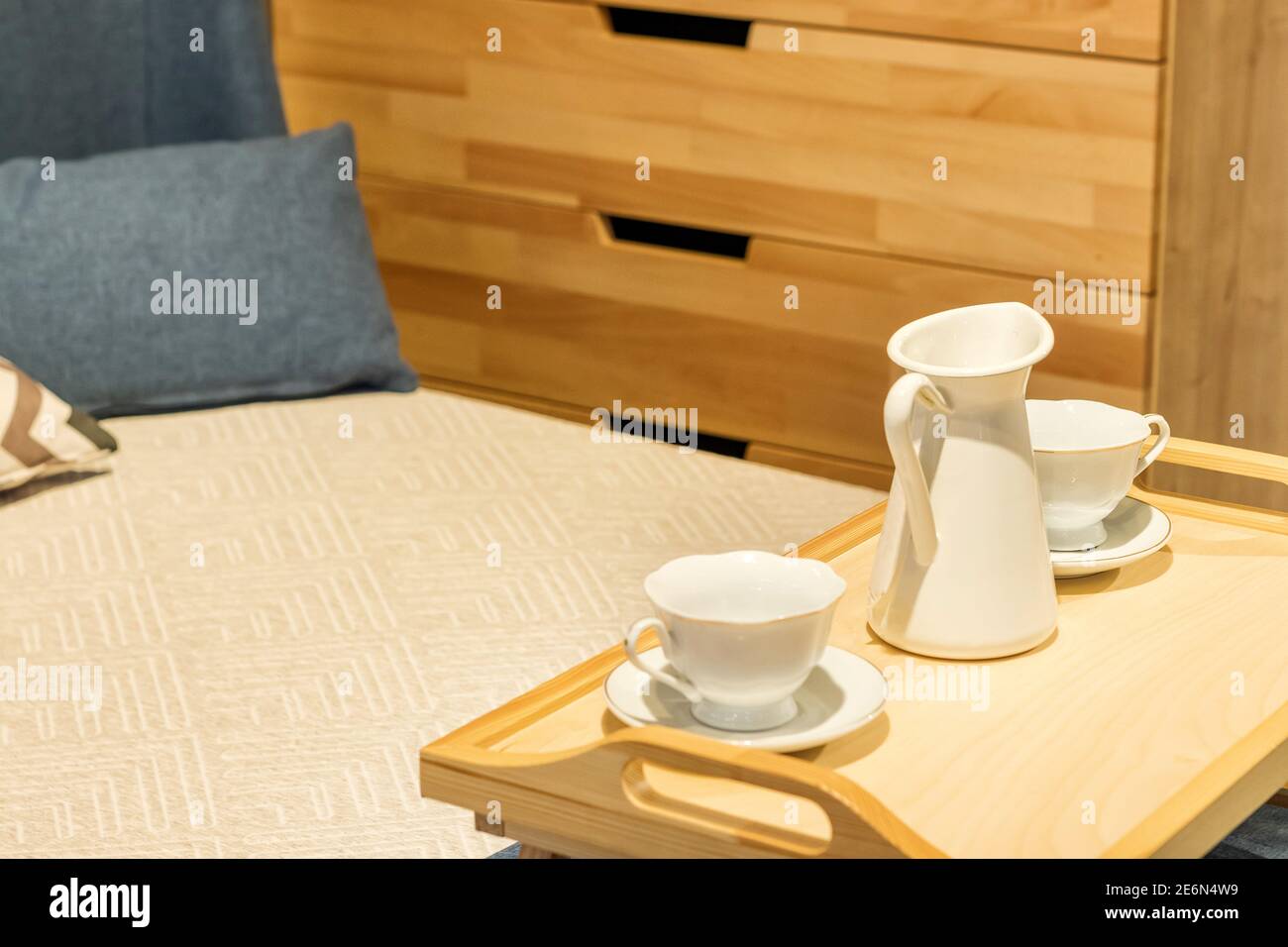 wooden tea table stands on the bed with cups. Bed with pillows and blue ...