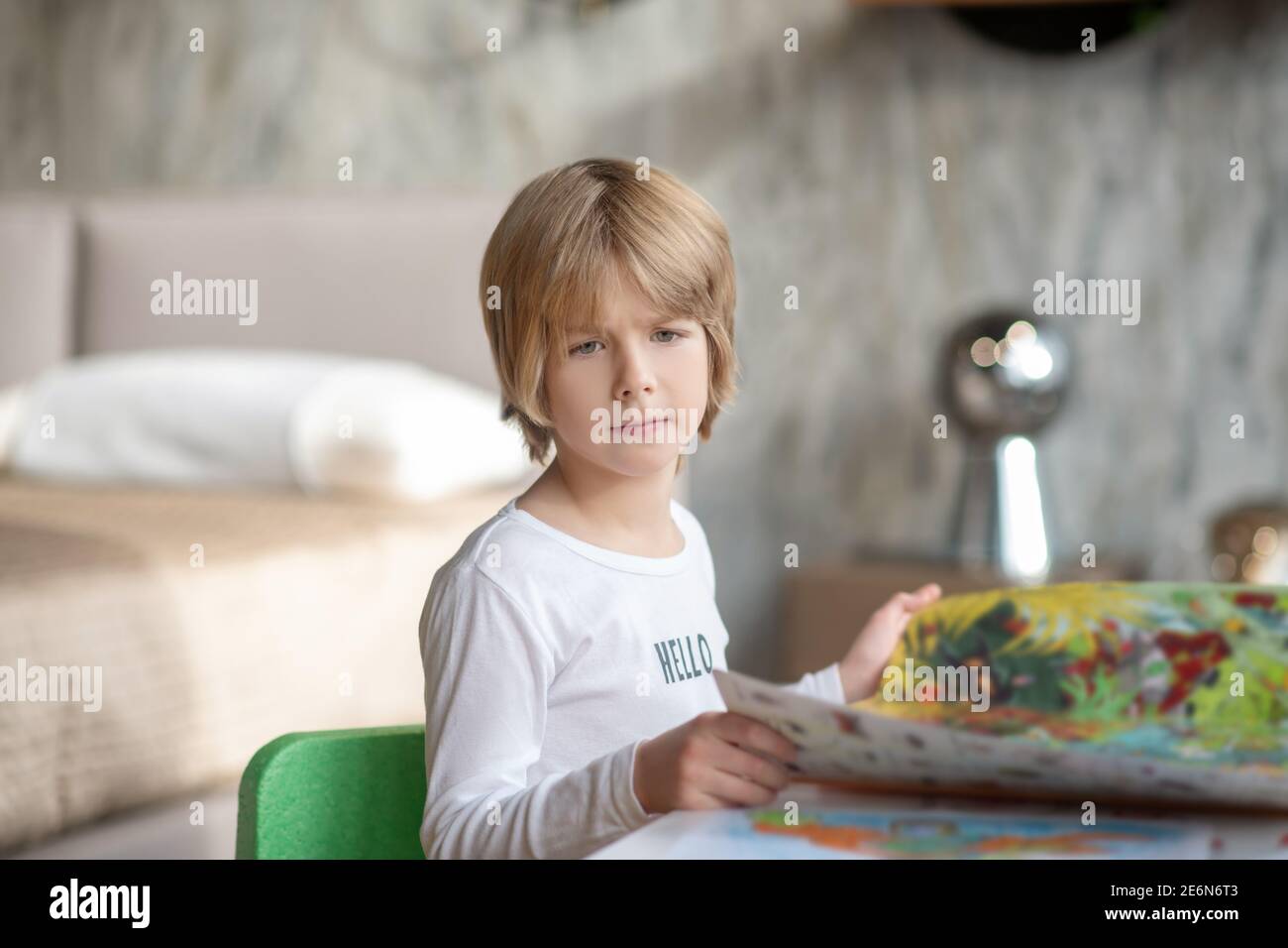 Fair-haired boy reading a magazine at home Stock Photo - Alamy