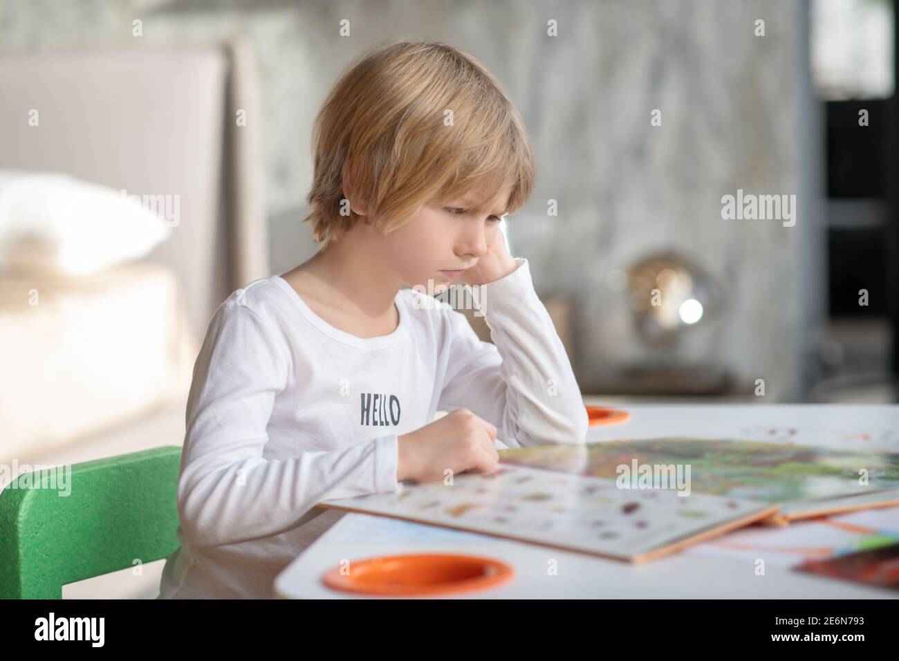 Bored young boyreading a book at home Stock Photo - Alamy