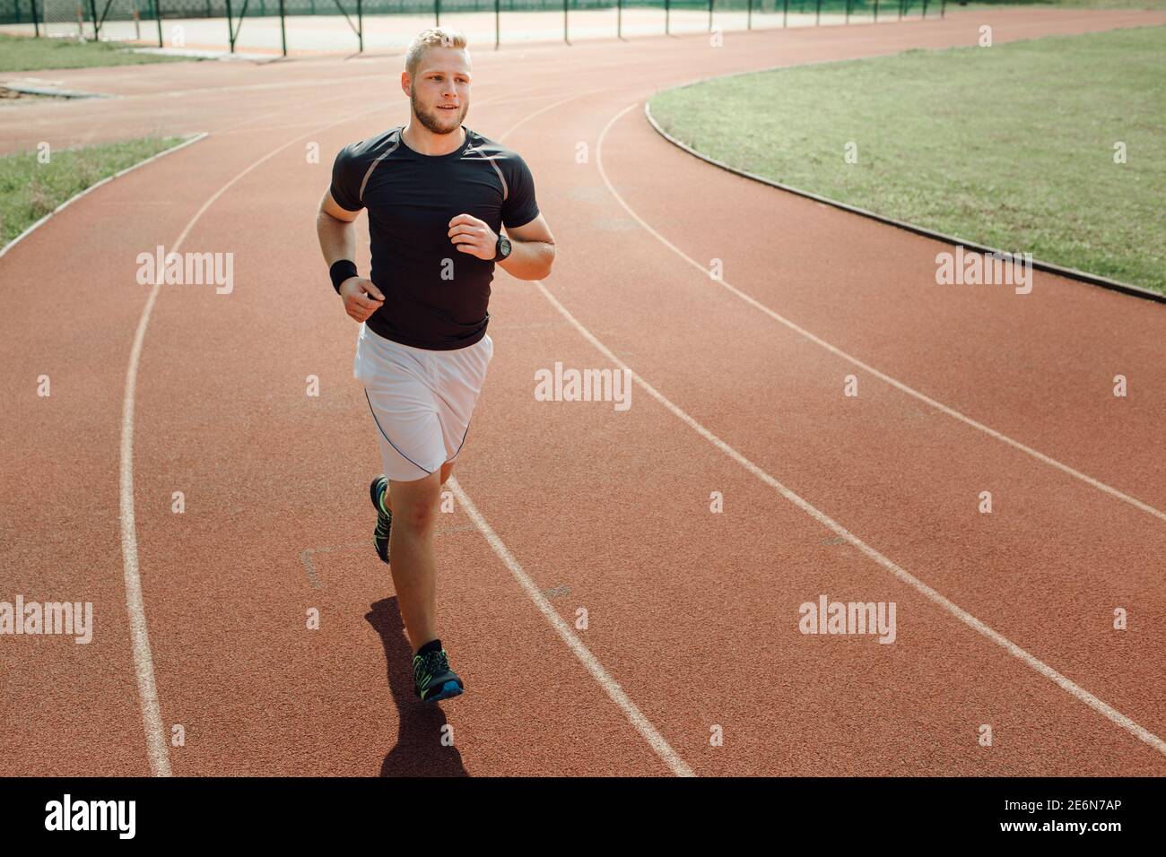 Cheerful male runner running at a field and track course Stock Photo ...