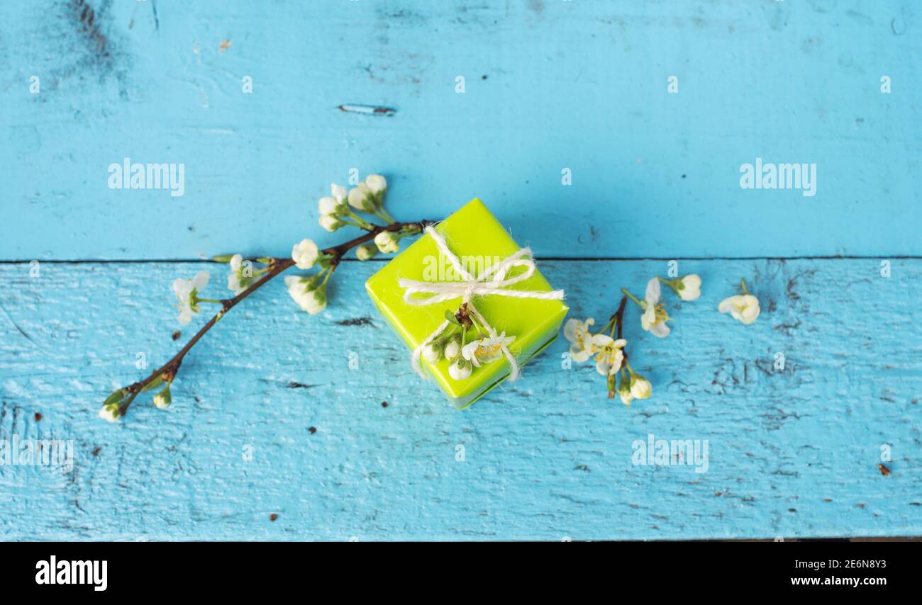 a box of light green color on a wooden blue background, spring flowers ...