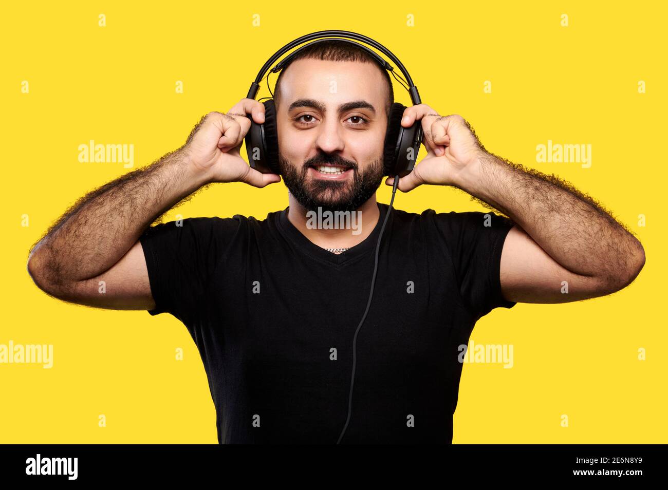 Positive bearded DJ with headphones laughing on a yellow background ...