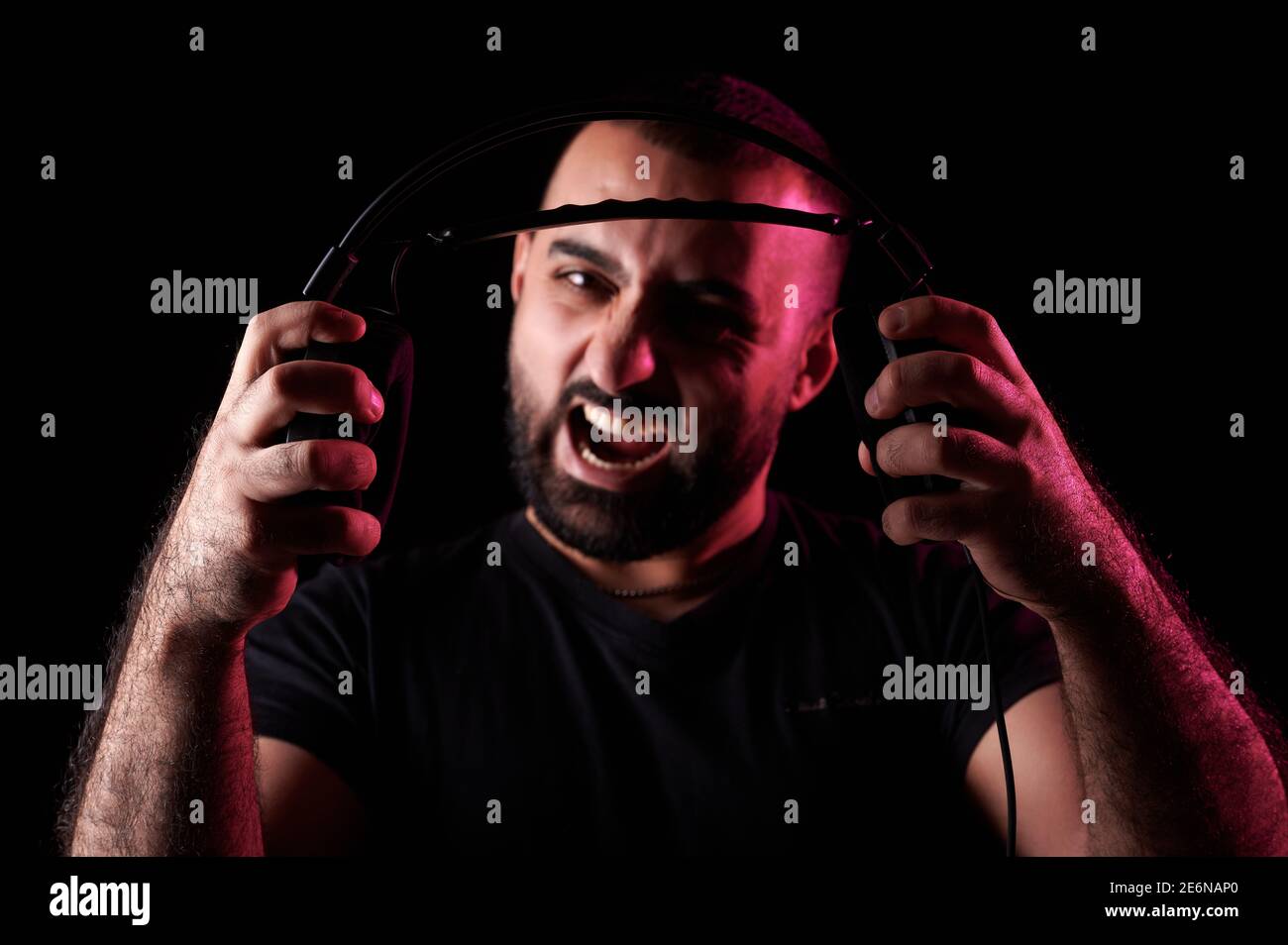 Angry screaming bearded arabic musician dj tearing headphones on black ...