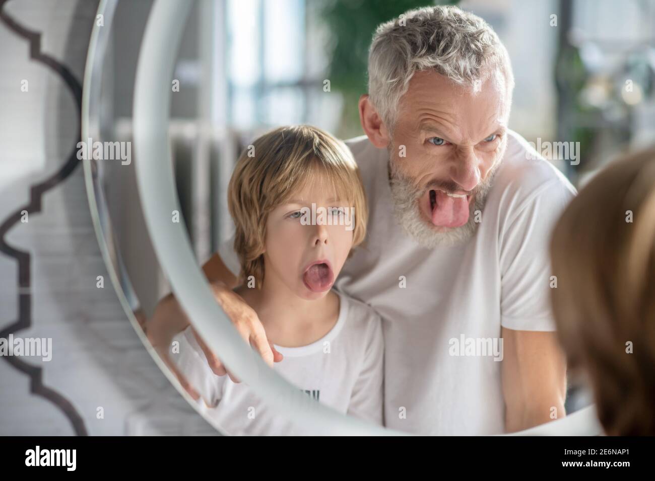 Man and his son making funny faces near the mirror Stock Photo - Alamy