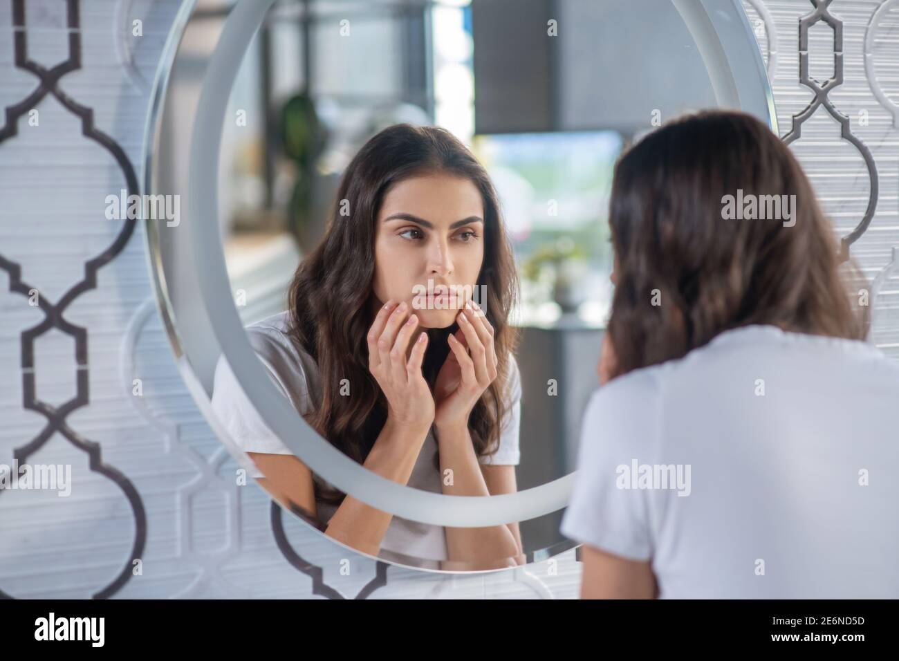 Woman looking at her reflection in the mirror Stock Photo - Alamy