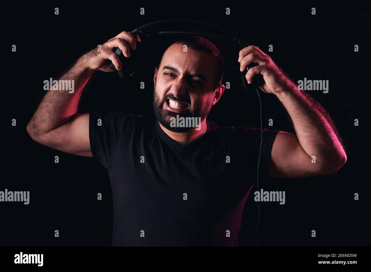 Angry screaming bearded arabic musician dj tearing headphones on black ...