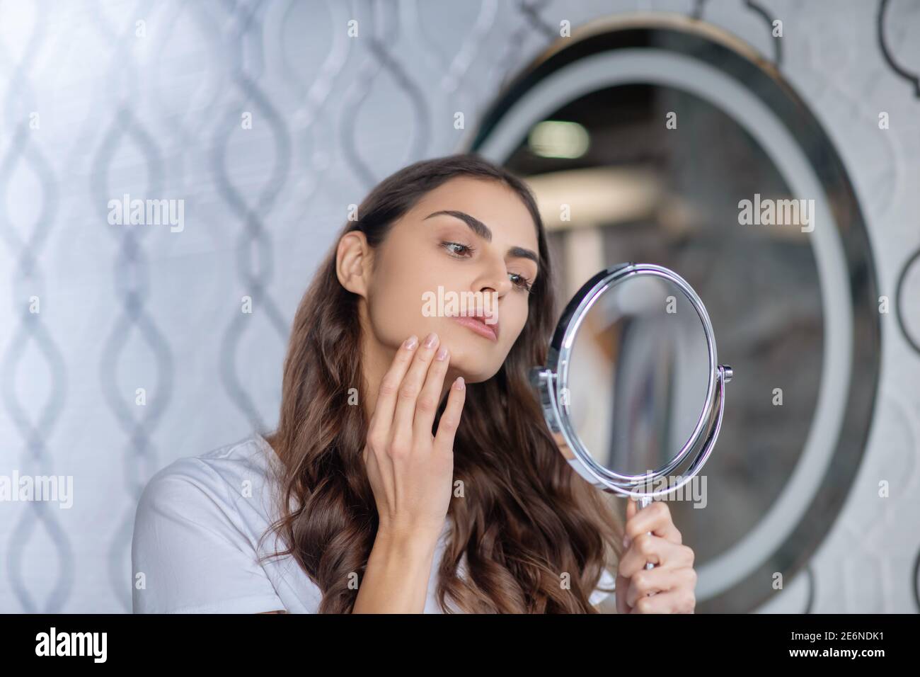 Woman checking her skin heath while looking at the mirror Stock Photo ...