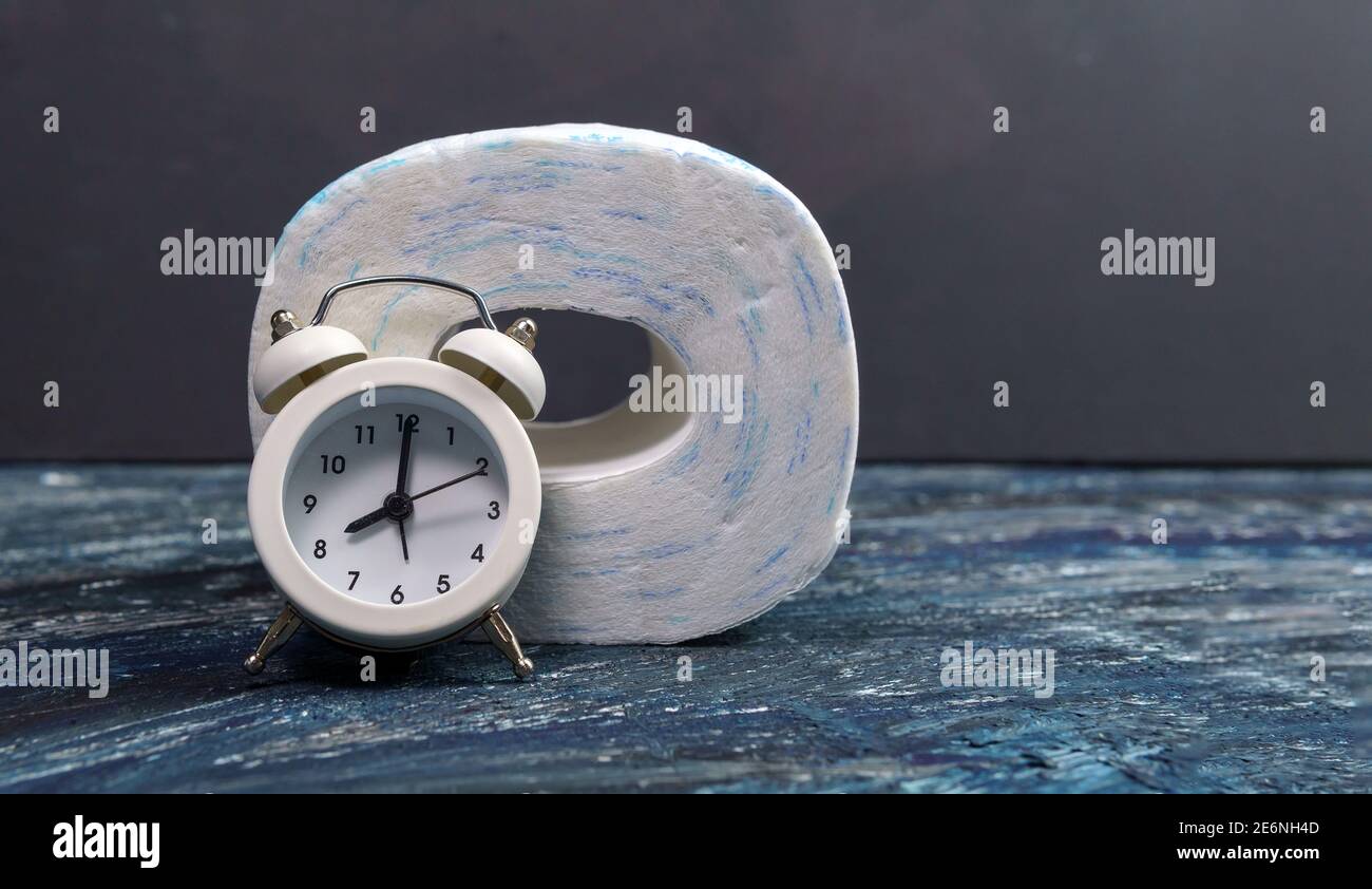 alarm clock and toilet paper. Concept of constipation, indigestion ...