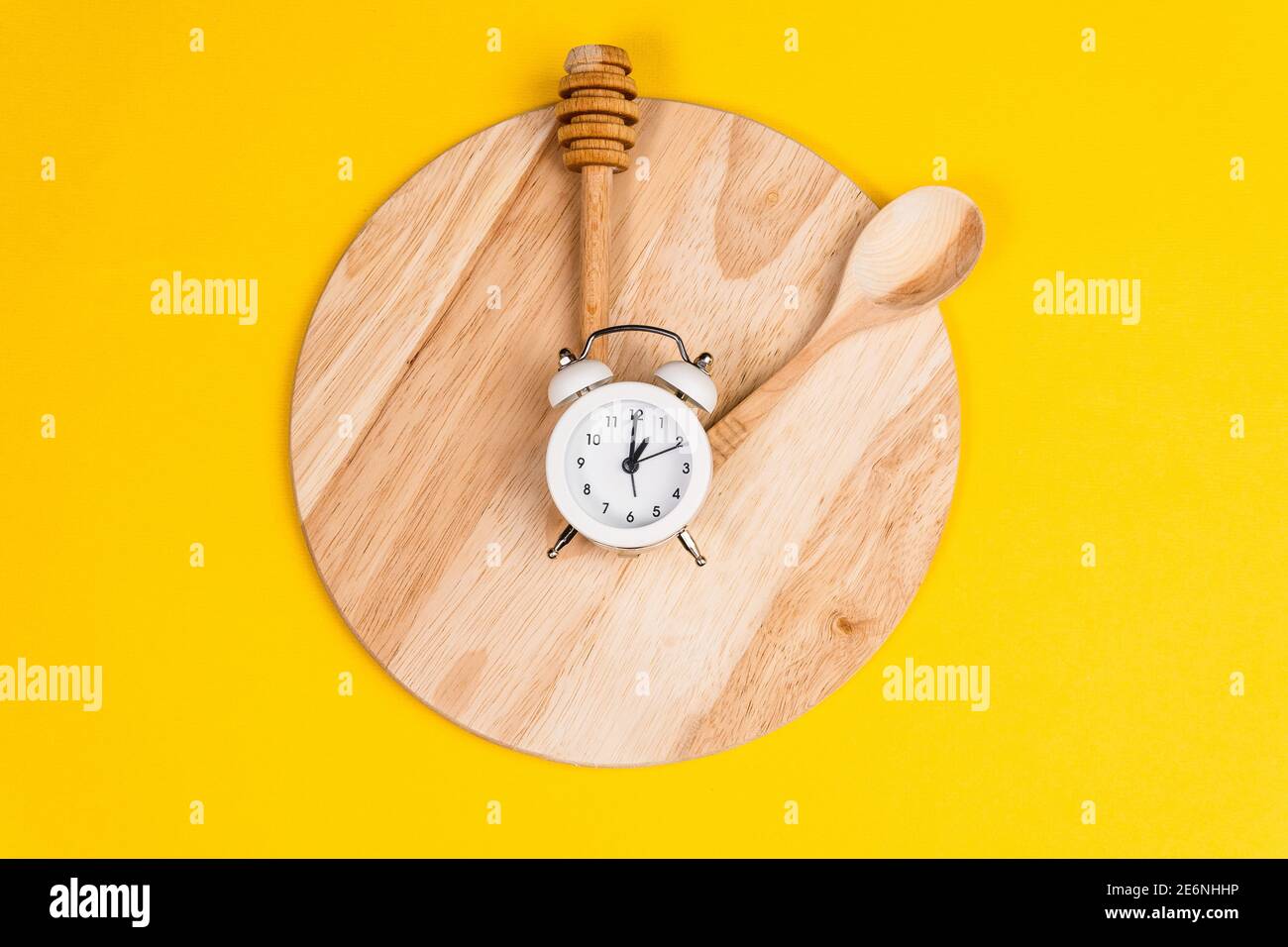 alarm clock with a spoon shows the time of the lunch break. yellow ...