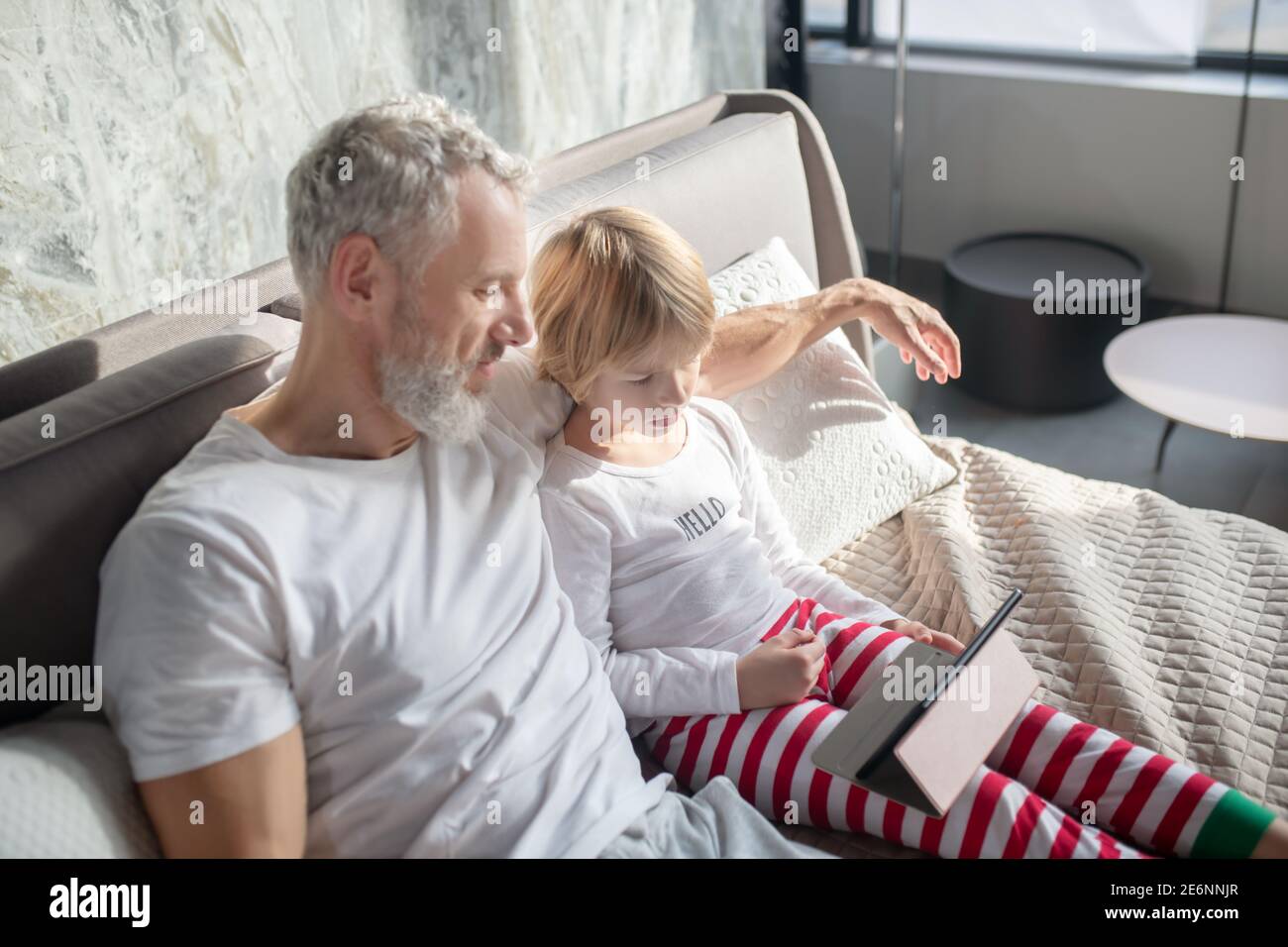 Attentive man and child looking into tablet together Stock Photo - Alamy