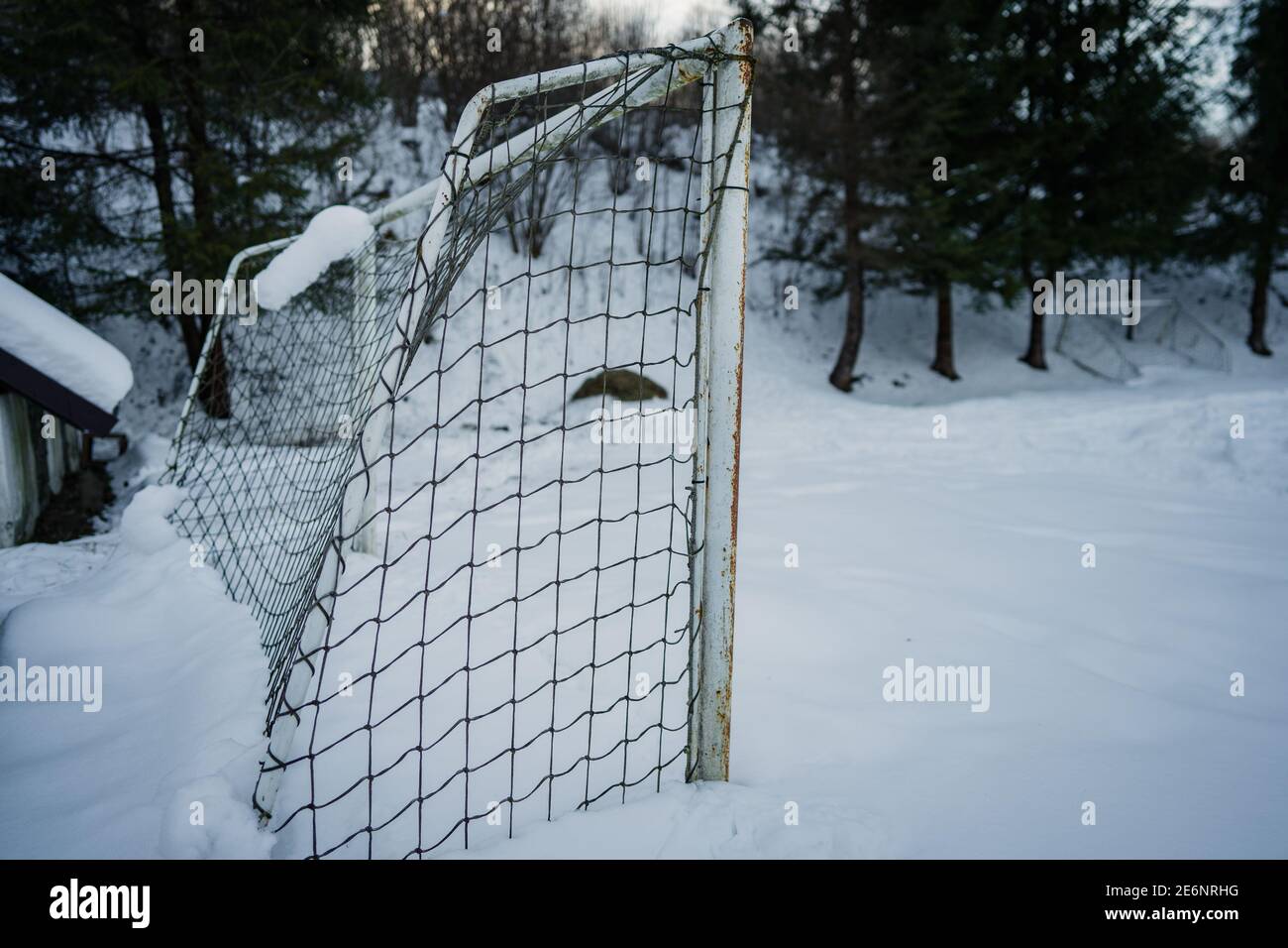 Look through net to football field in soccer stadium covered with snow ...
