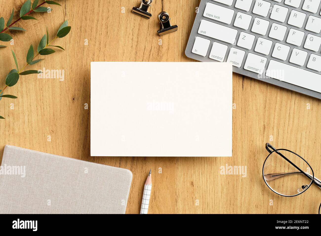 Blank paper card on wood office desk table with keyboard, eucalyptus ...