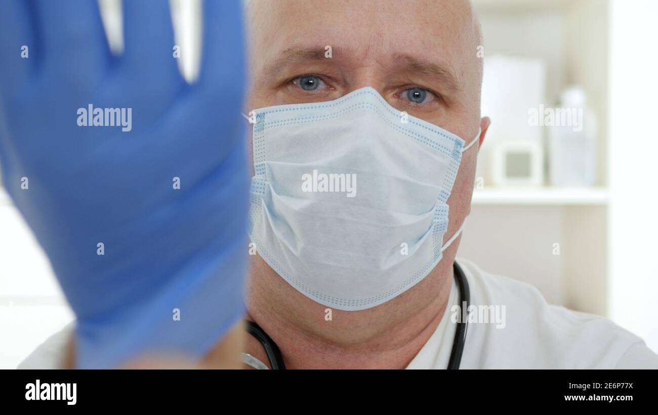 Doctor Wearing Protective Face Mask, Puts Surgical Gloves on His Hands ...
