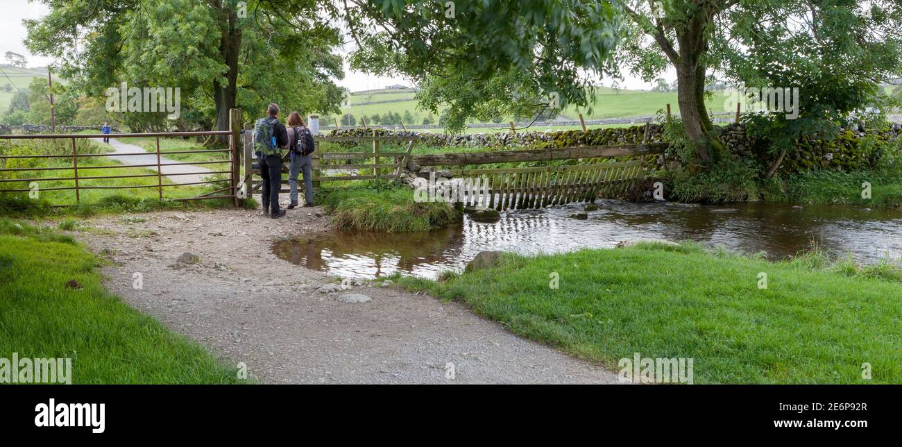 Walkers passing through a gate on a footpath running next to Malham ...