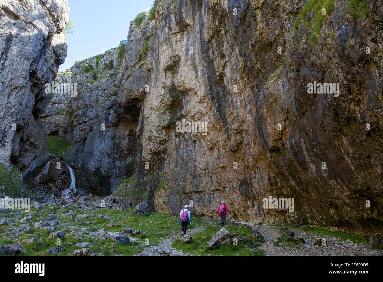 Two walkers on a path at Gordale Scar, an impressive limestone gorge ...