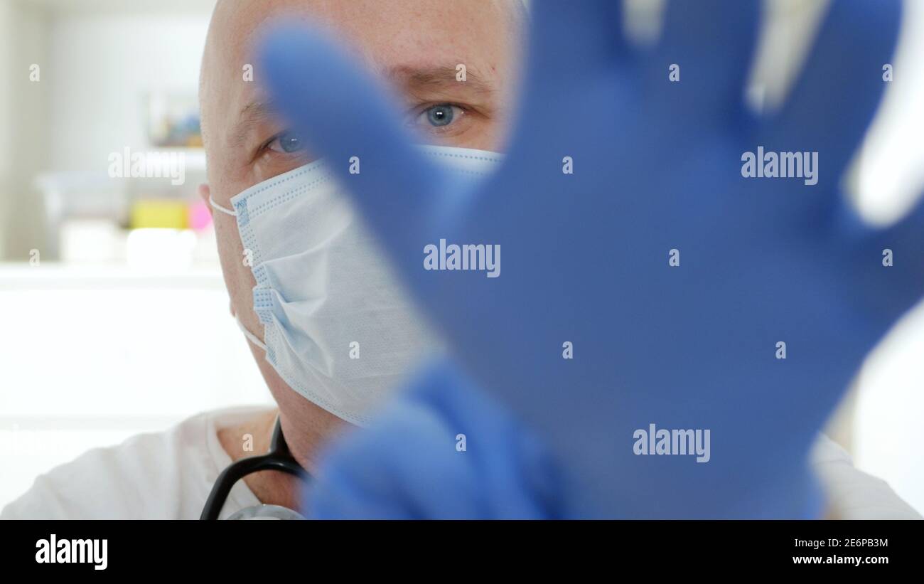 Doctor Wearing Protective Face Mask, Puts Surgical Gloves on His Hands ...