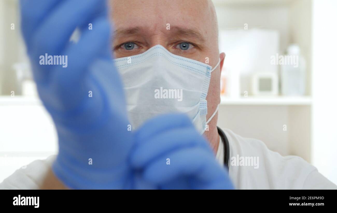 Doctor Wearing Protective Face Mask, Puts Surgical Gloves on His Hands ...