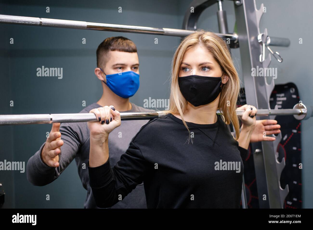 Young woman with protective mask working out with personal trainer at ...