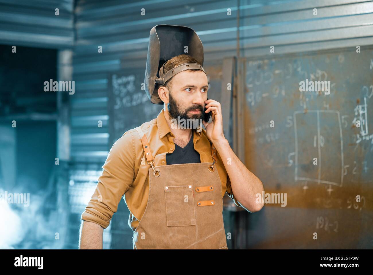 Welder with phone at the workshop Stock Photo - Alamy