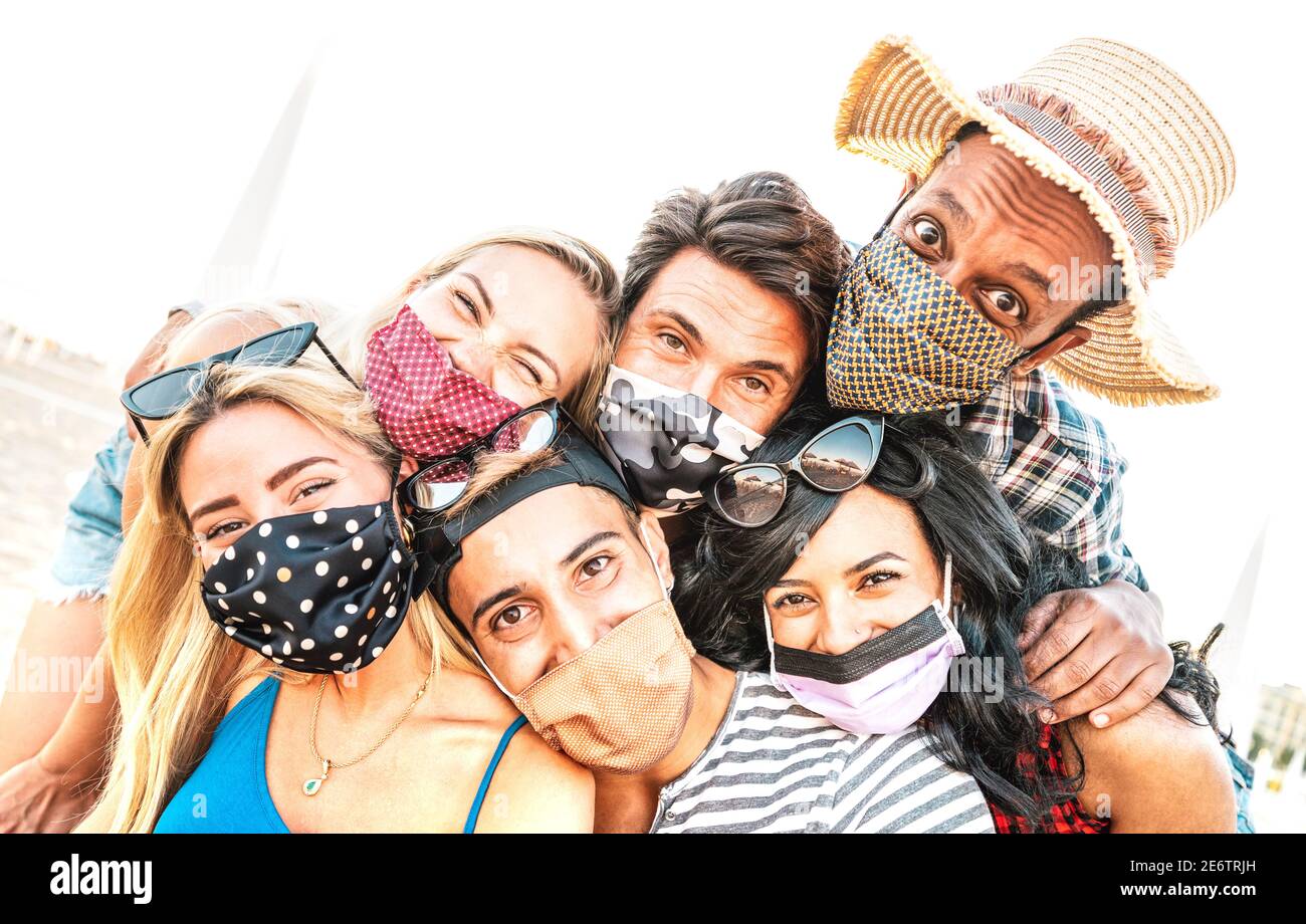 Multiracial milenial friends taking selfie smiling behind face masks ...