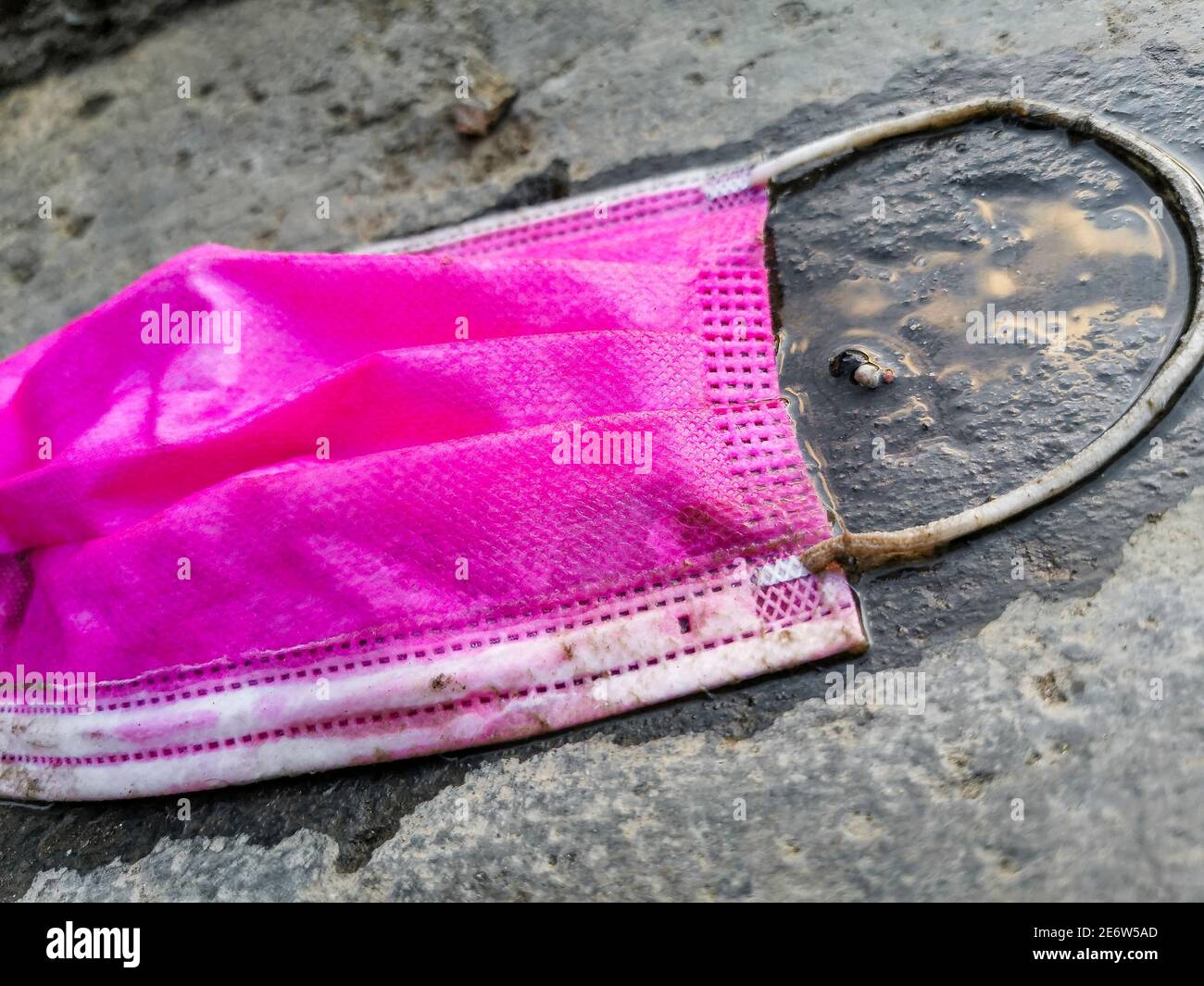 Dirty surgical pink masks on the ground. Corona virus pollution ...