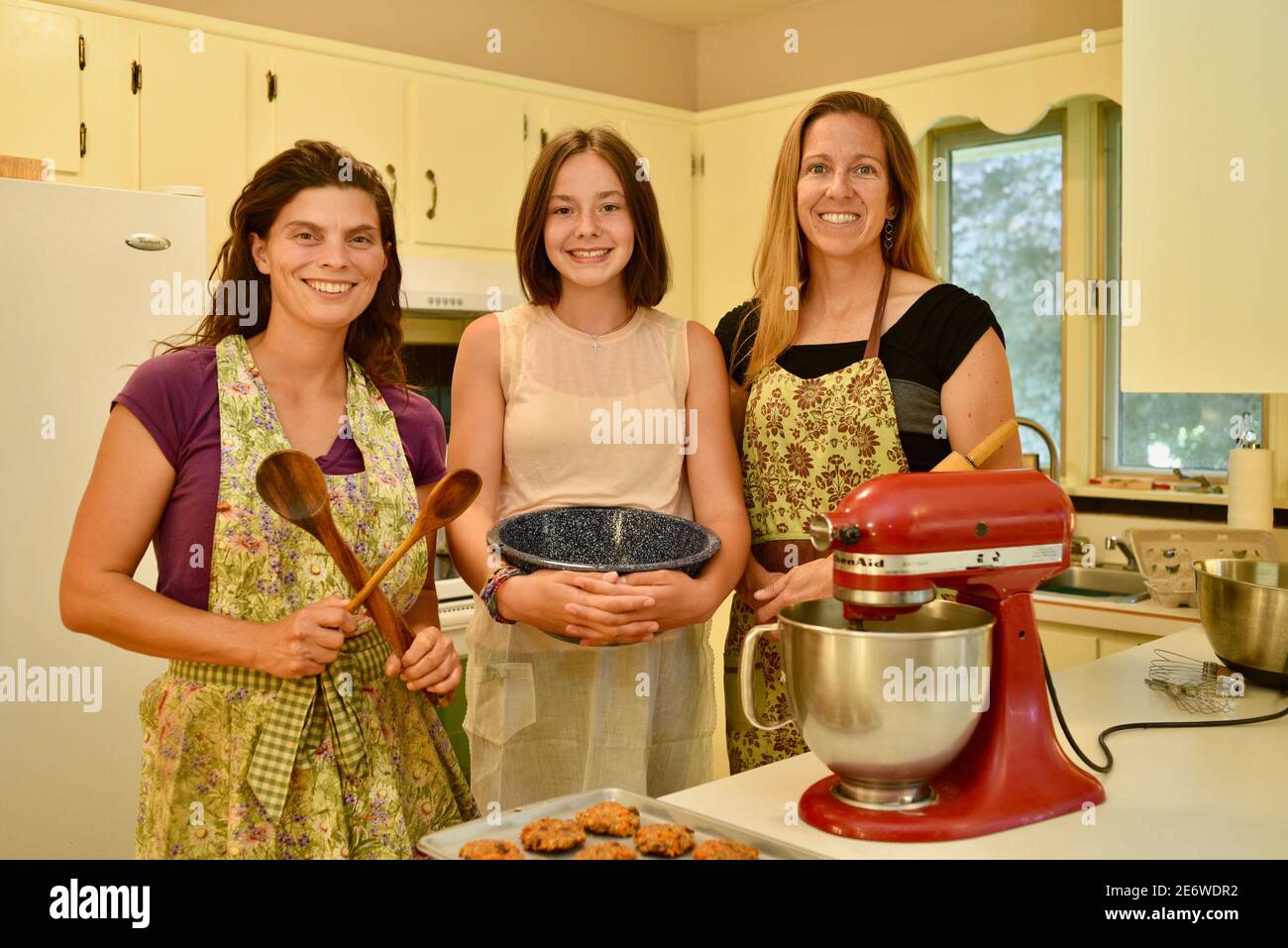 Three attractive adult caucasian women home bakers with mixing bowl and ...