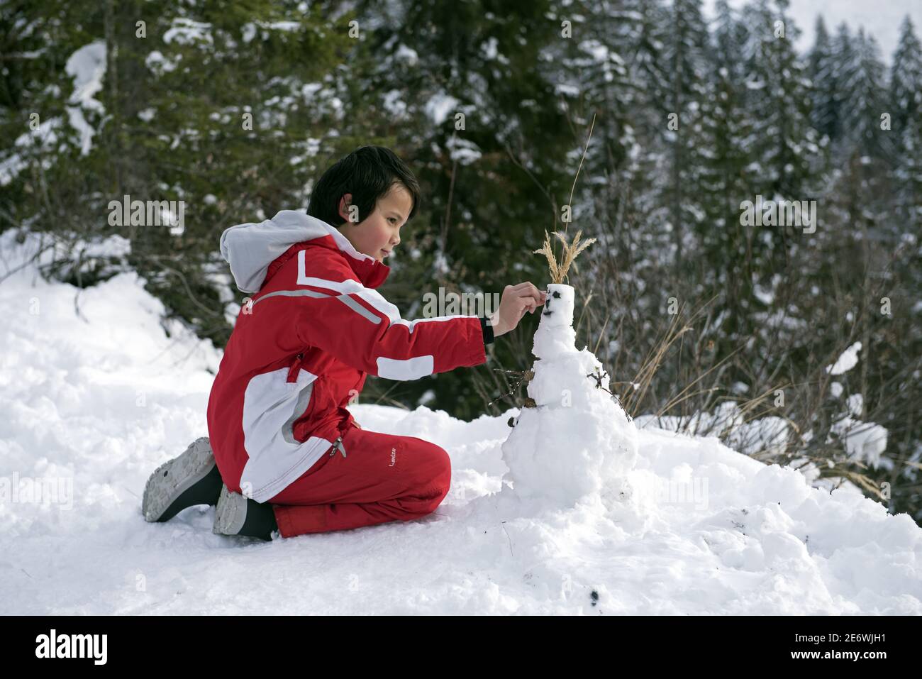 Boy making a little snowman Stock Photo - Alamy