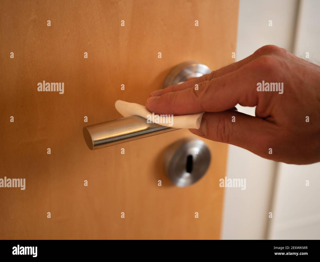 Man cleaning door handle with disinfectant wipe Stock Photo - Alamy
