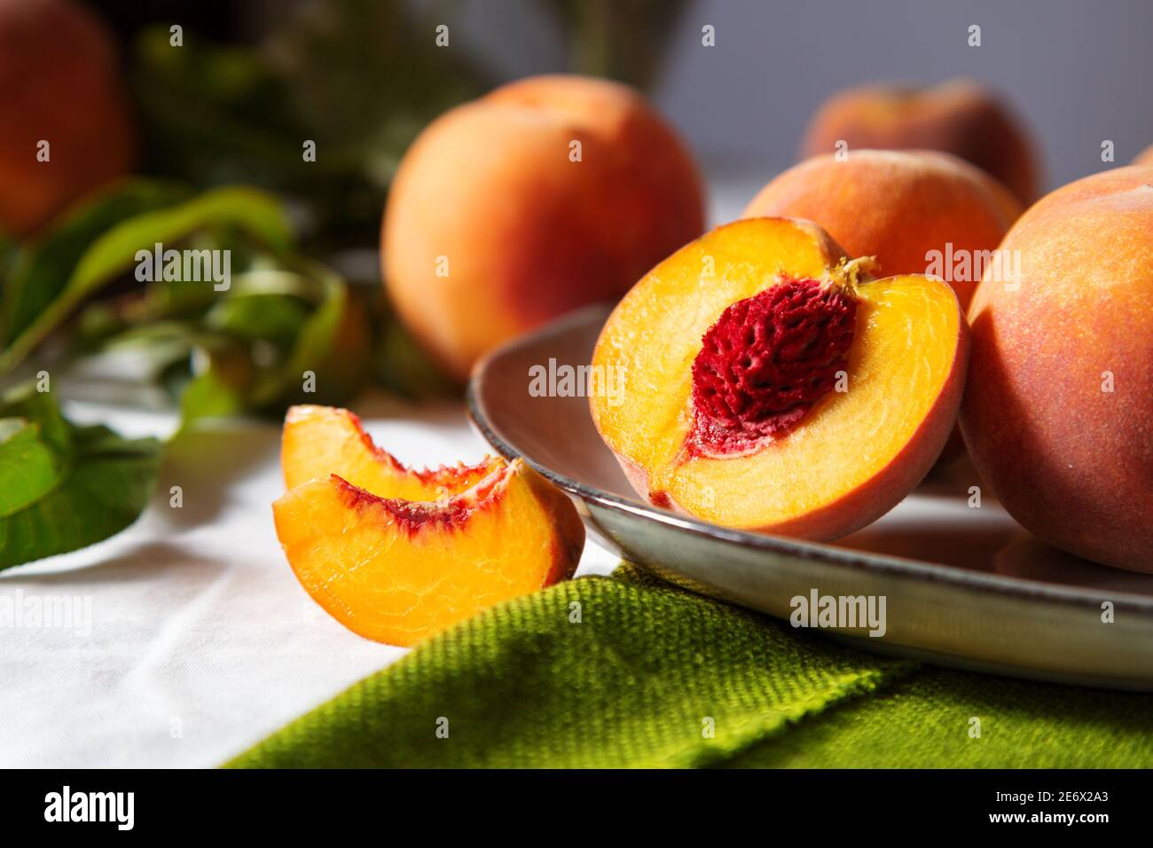 Peach in halves with bone. Peaches with leaves on color green plate on ...