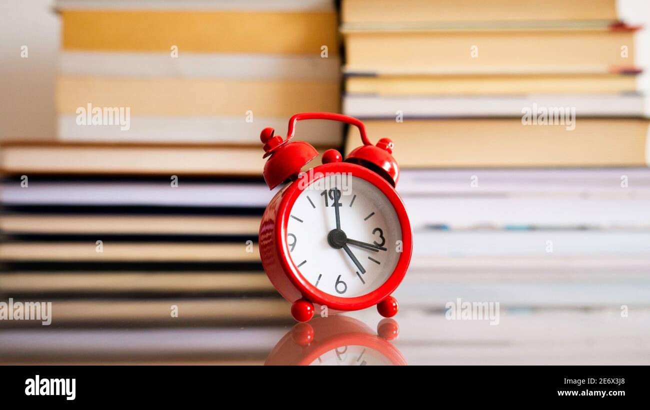 Time to study. Alarm clock in front of books Stock Photo - Alamy
