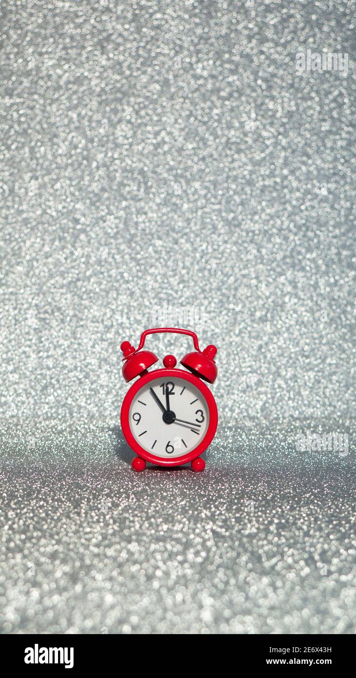 The red clock shows five minutes to twelve on a silver glitter ...