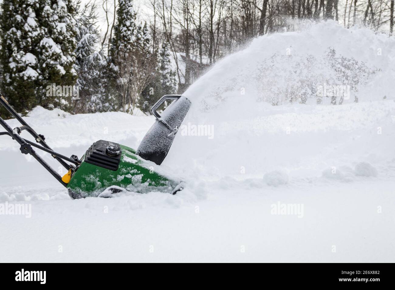 Snow blower in action clearing a residential driveway after snow storm ...