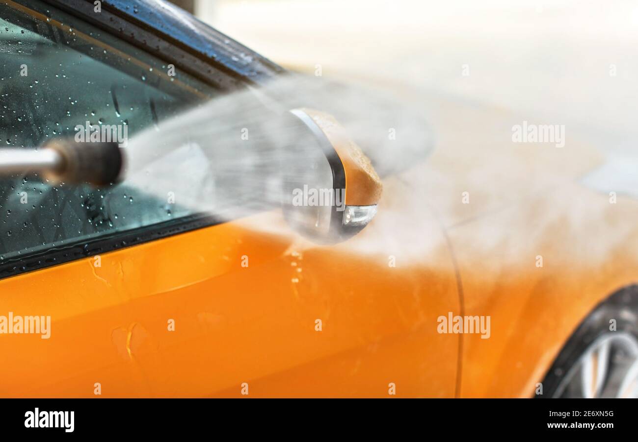 Side mirror of yellow car being washed in self service carwash, water ...