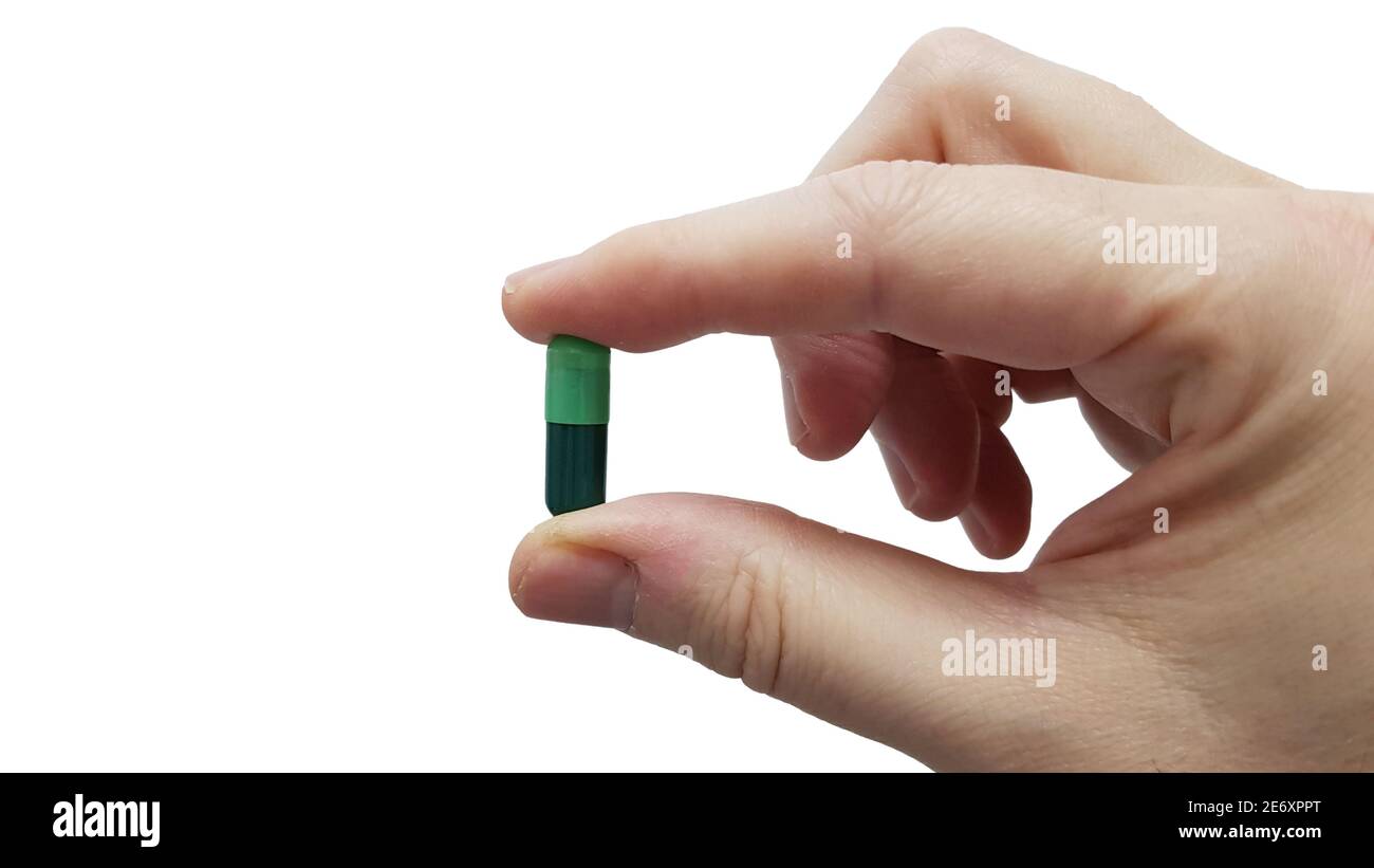 Hand holding a green capsule on a white background Stock Photo - Alamy