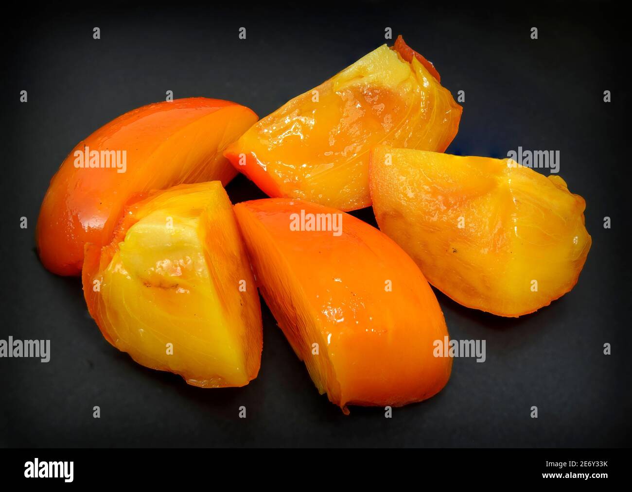 sliced ripe and juicy fruit of a sharon on a black background Stock ...
