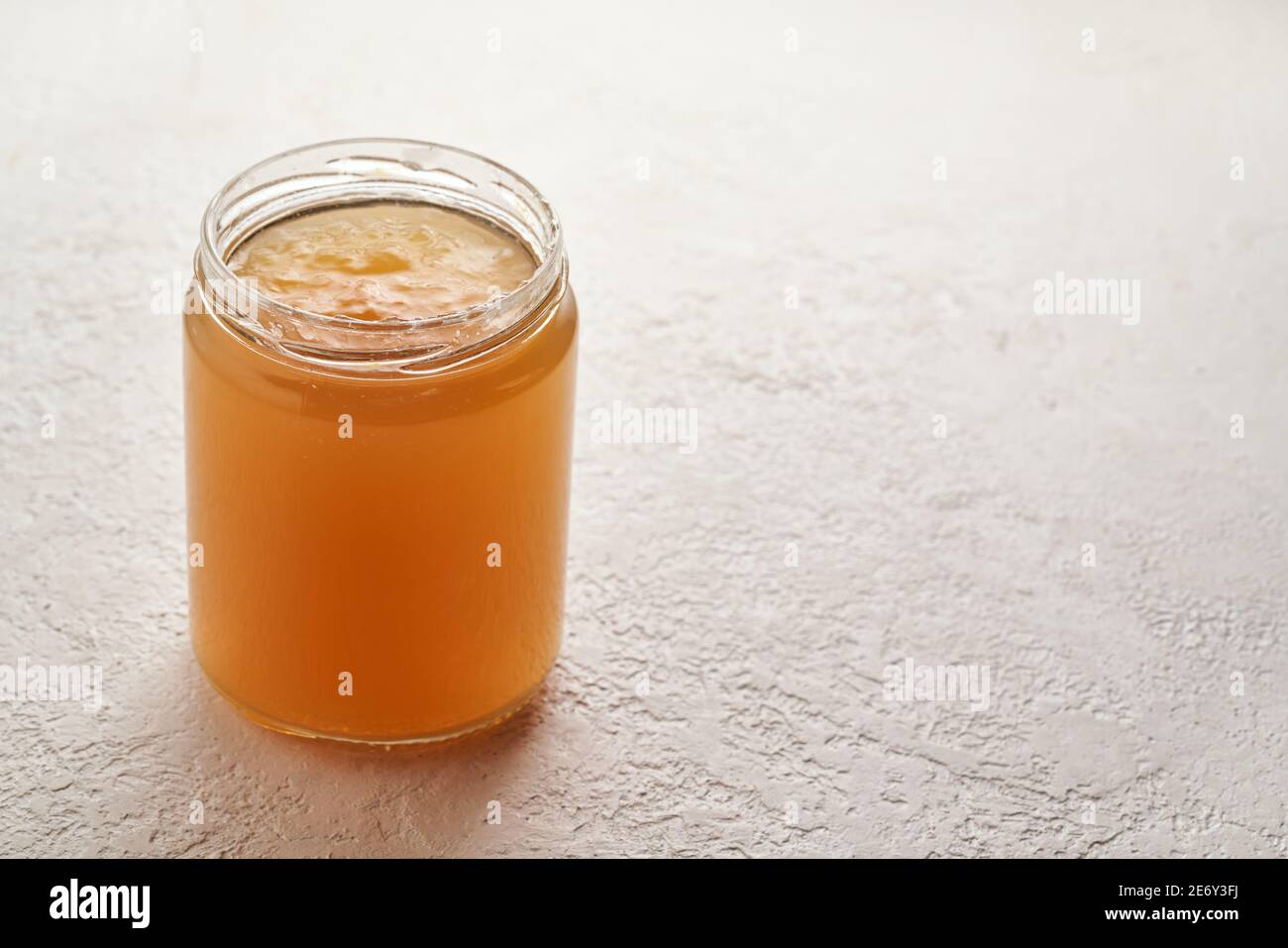 A jar of cooled down congealed beef bone broth on a white background ...