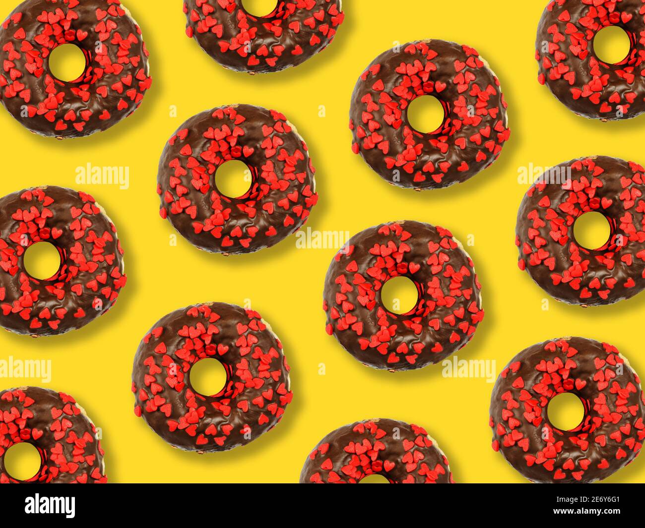 Flat lay donuts in chocolate glaze pattern on a yellow background. Top ...
